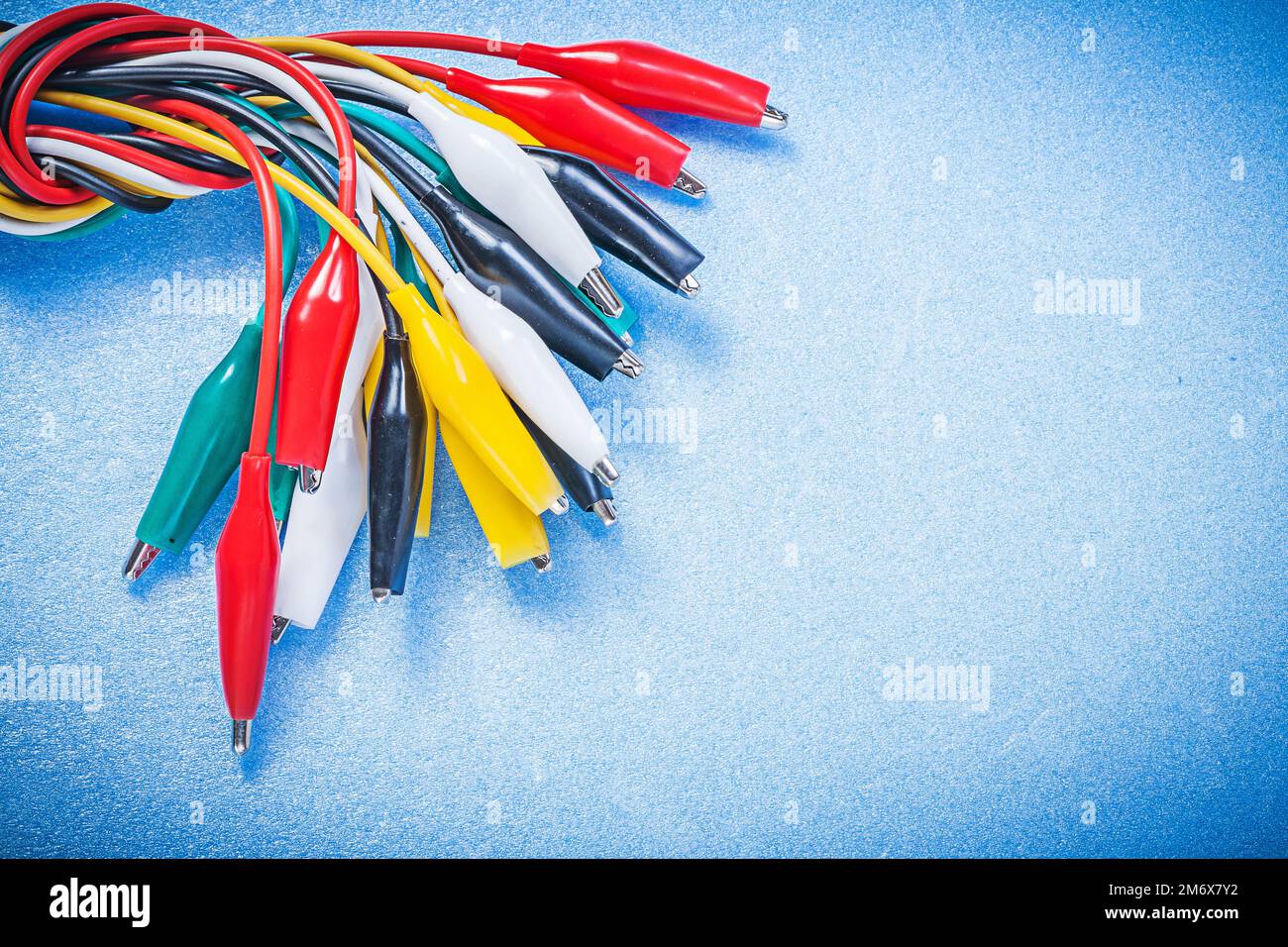 Assortment of electric crocodile clip cables on blue background ...