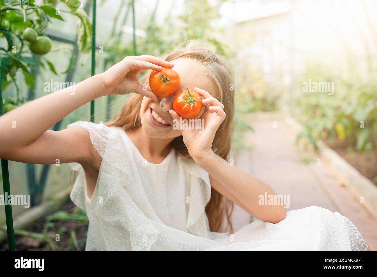 Adorable girl having fun in greenhouse. Portrait of kid with basket ...