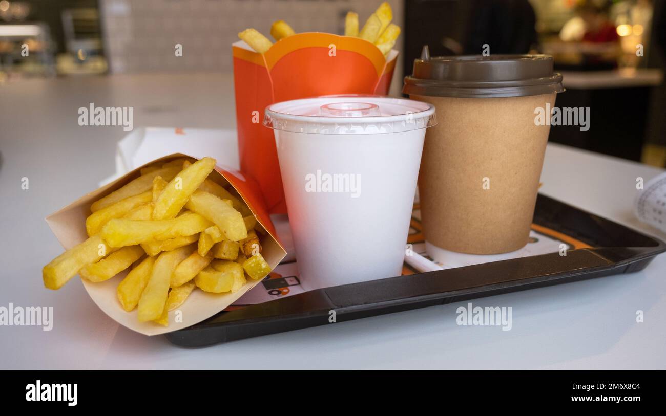 Fast food on a tray in a restaurant. French fries, a glass with a ...