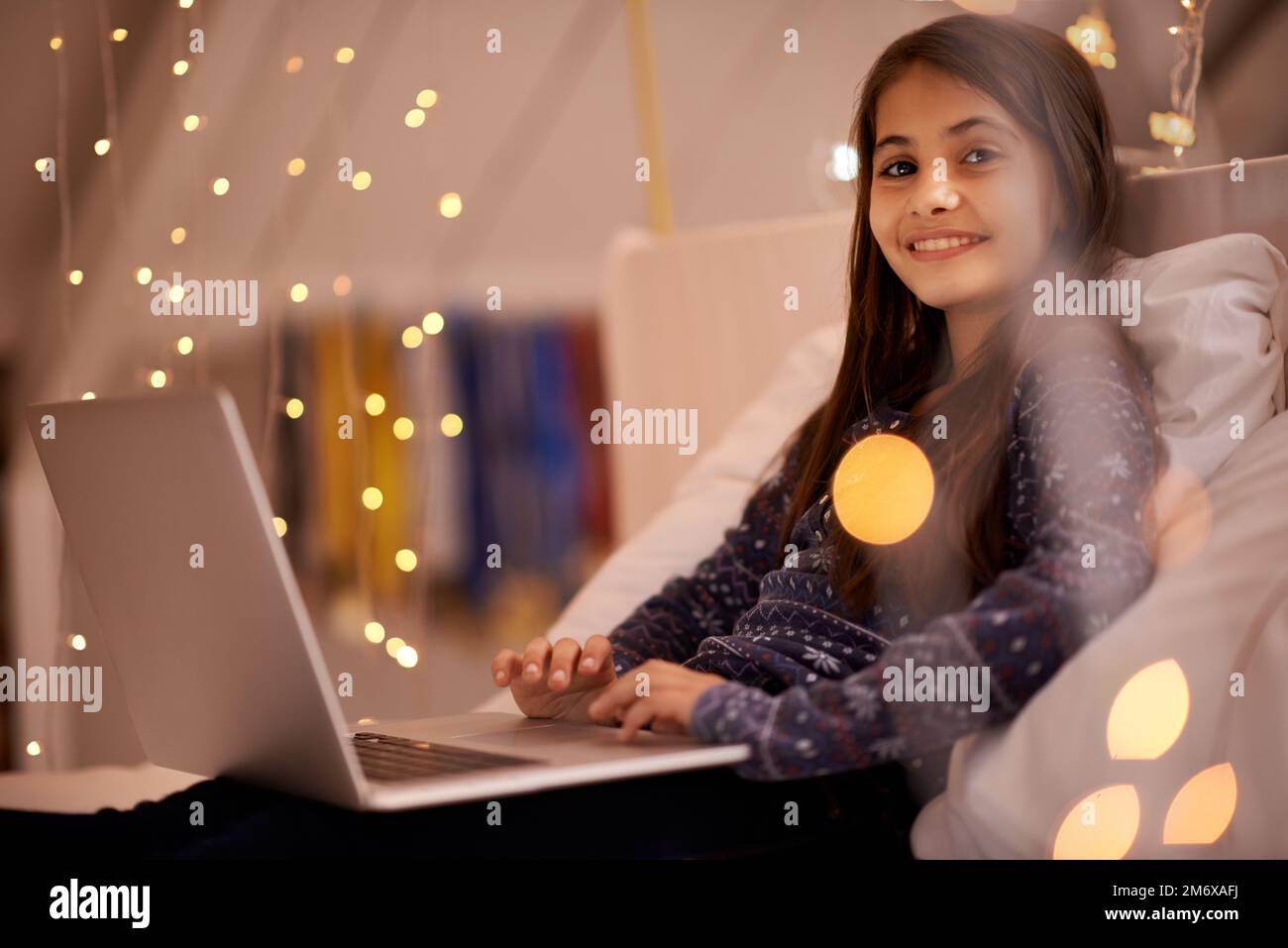 Techno teen. Portrait of a cute little girl using a laptop at home ...
