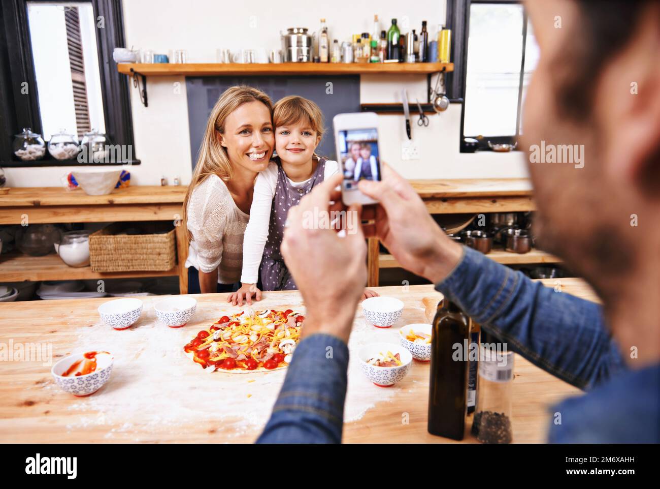 Say Mozzarella. A dad taking a photo of his family making homemade ...