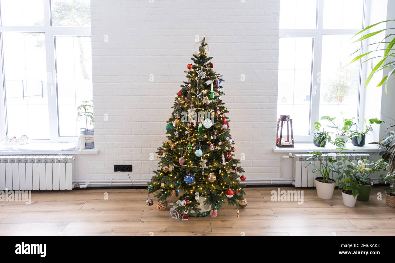 Christmas tree in the white interior of a house with large windows ...