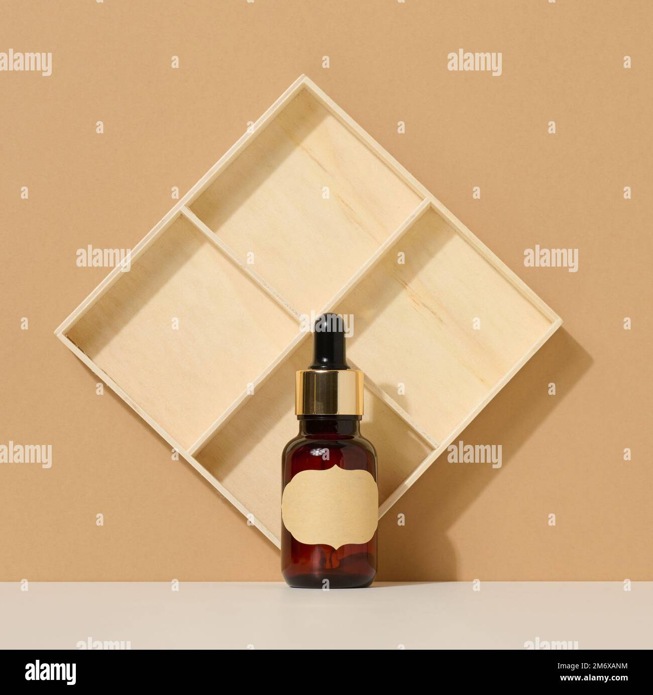 A brown glass bottle with a paper label and a pipette on a white table ...