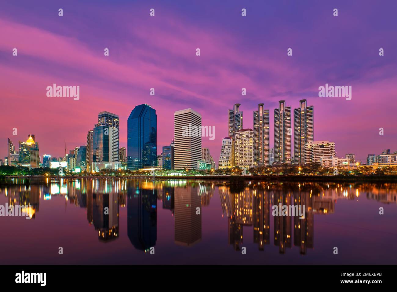 Asian modern highrises reflect in lake waters at sunset. Bangkok ...