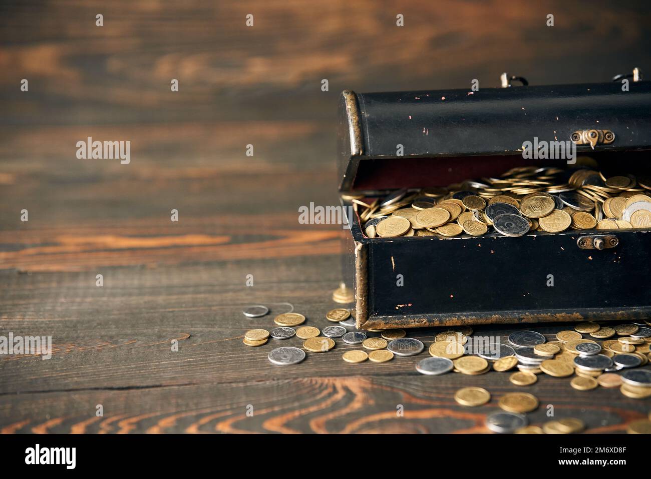 Chest full of coin on wooden background with copy space for your text ...