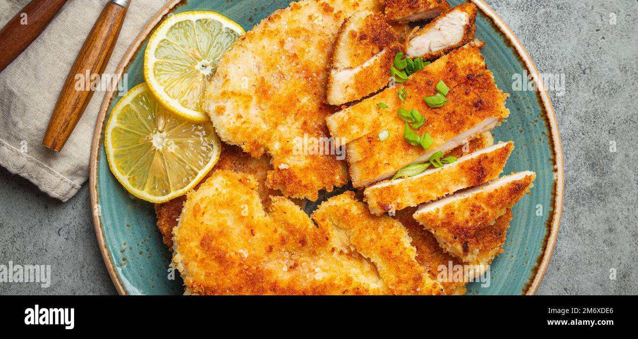 Crispy panko breaded fried chicken fillet with green salad and lemon ...