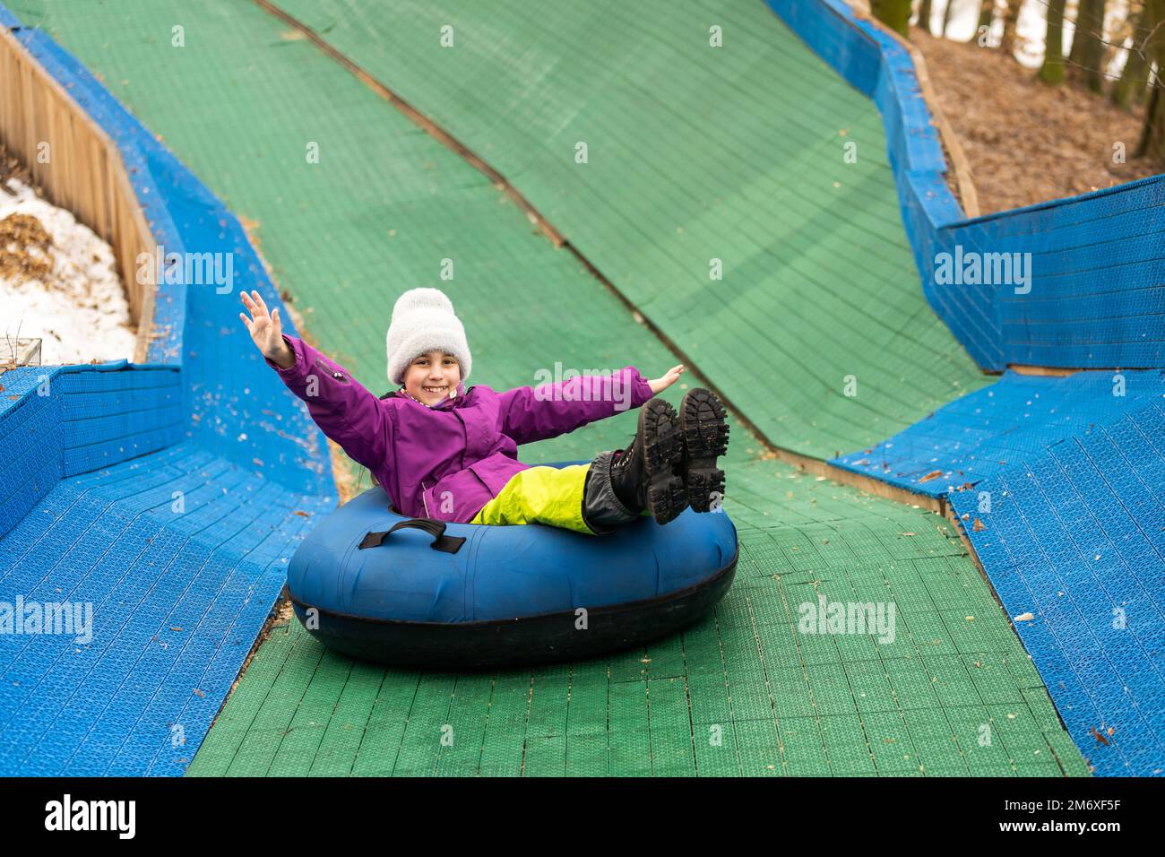 Little girl sliding downhill on tube Stock Photo - Alamy