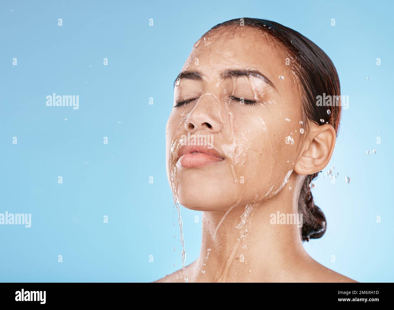 Woman, face skincare or water splash on blue background studio for healthcare wellness, Brazil ...
