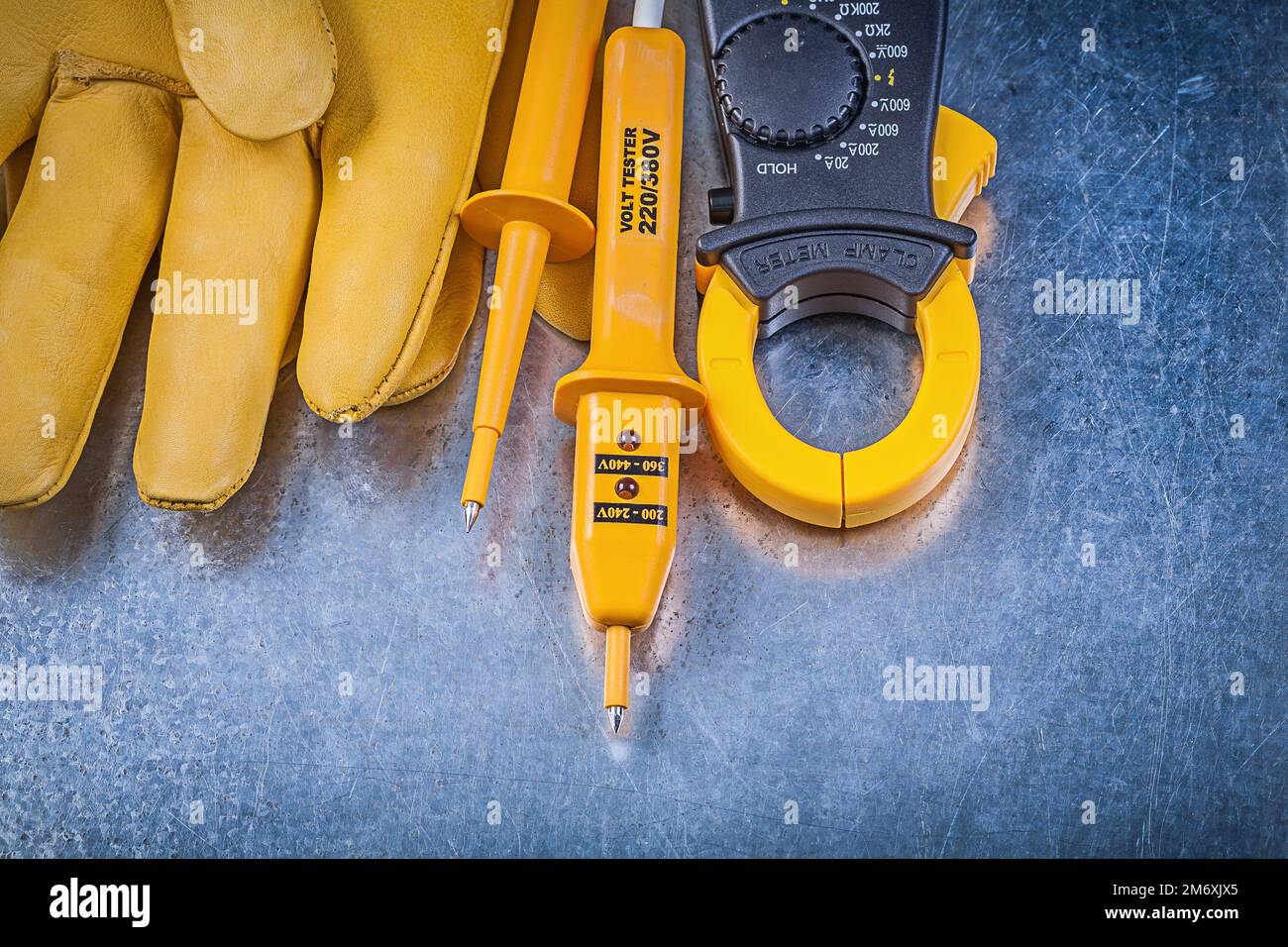 Digital amperemeter electrical tester safety gloves on metallic surface ...