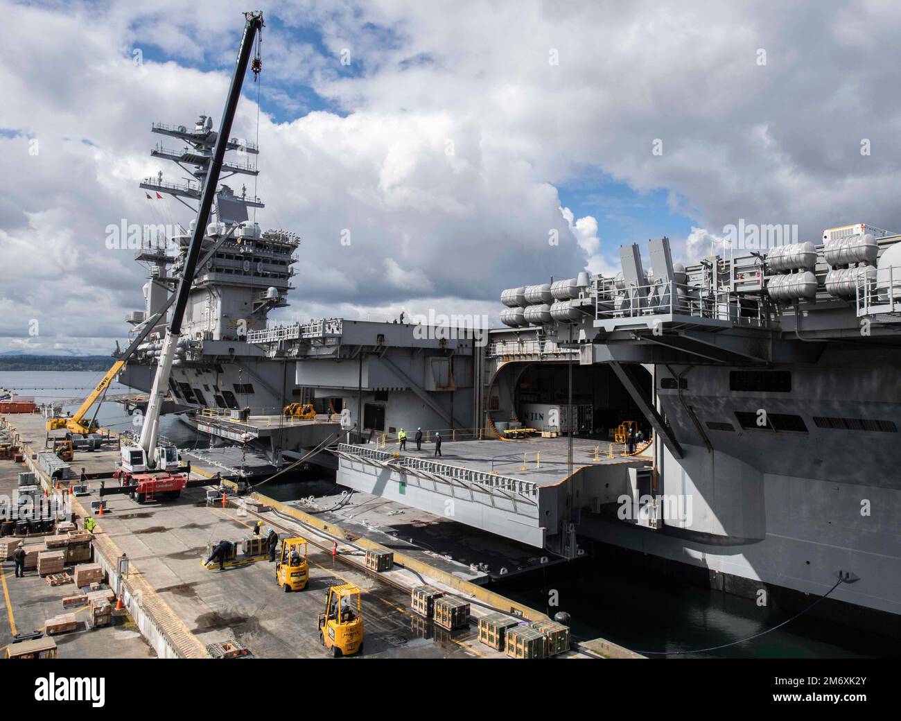Crews load munitions onto the aircraft carrier USS Nimitz (CVN 68) in ...
