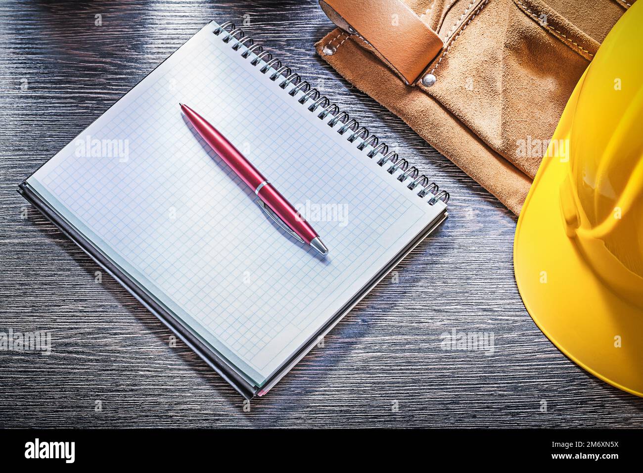 Leather construction belt building helmet notepad pen on wooden board ...