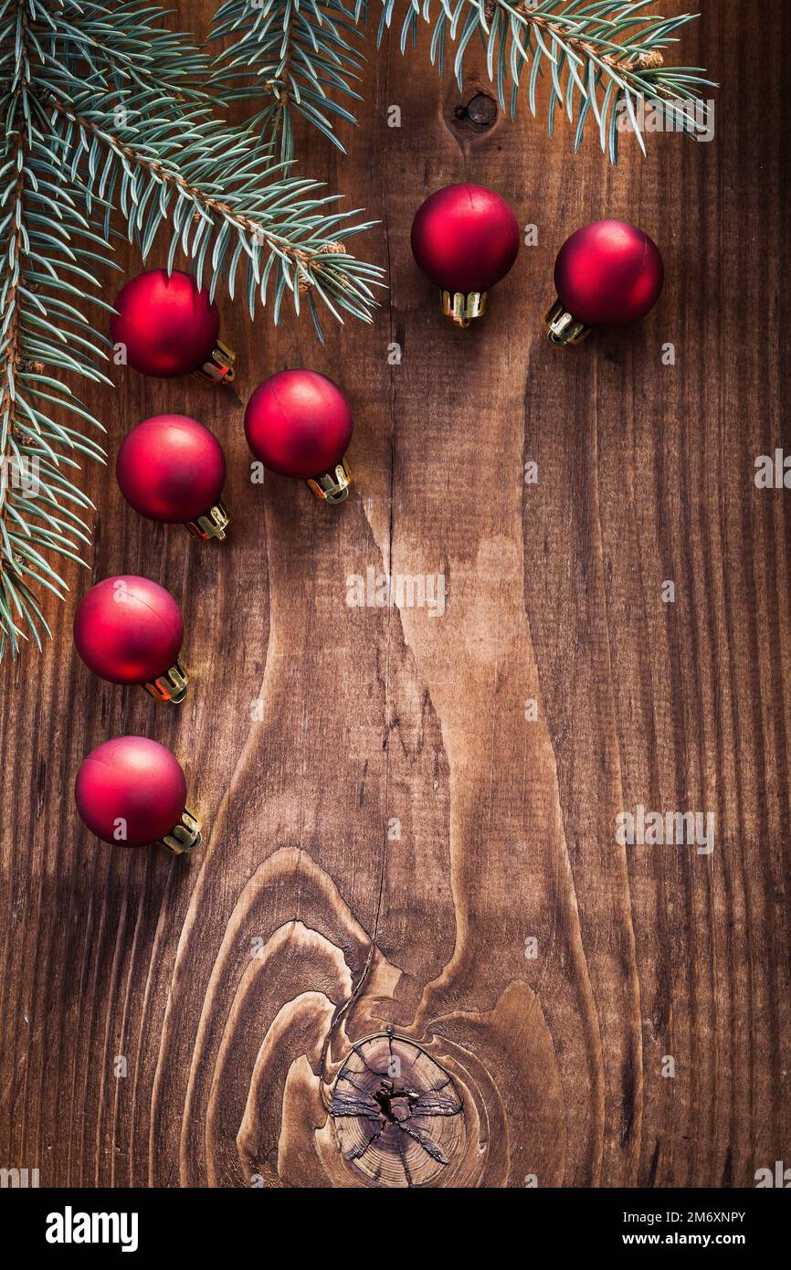 little red christmas baubles with branches of firtree on old wooden ...