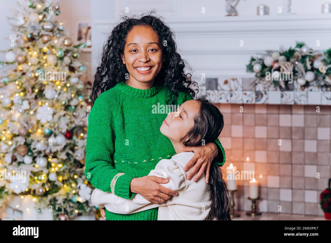 Brunette long-haired daughter and African American curly mother pose ...