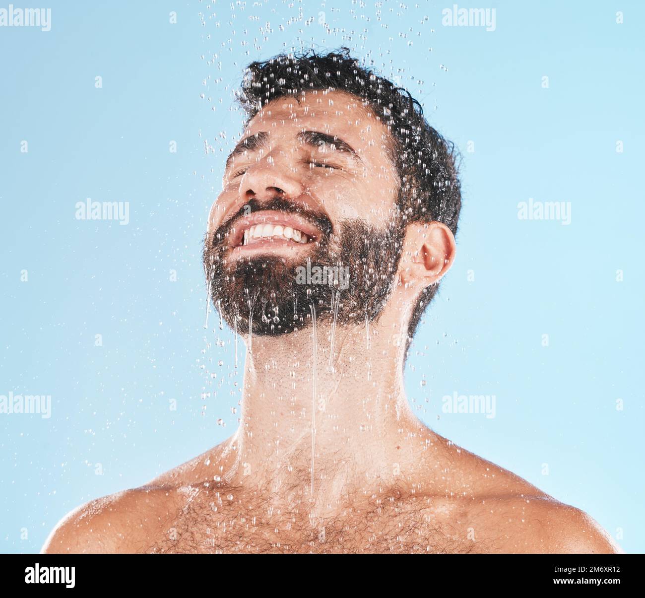 Man, shower and water for cleaning, studio and self care wellness with smile by blue background ...