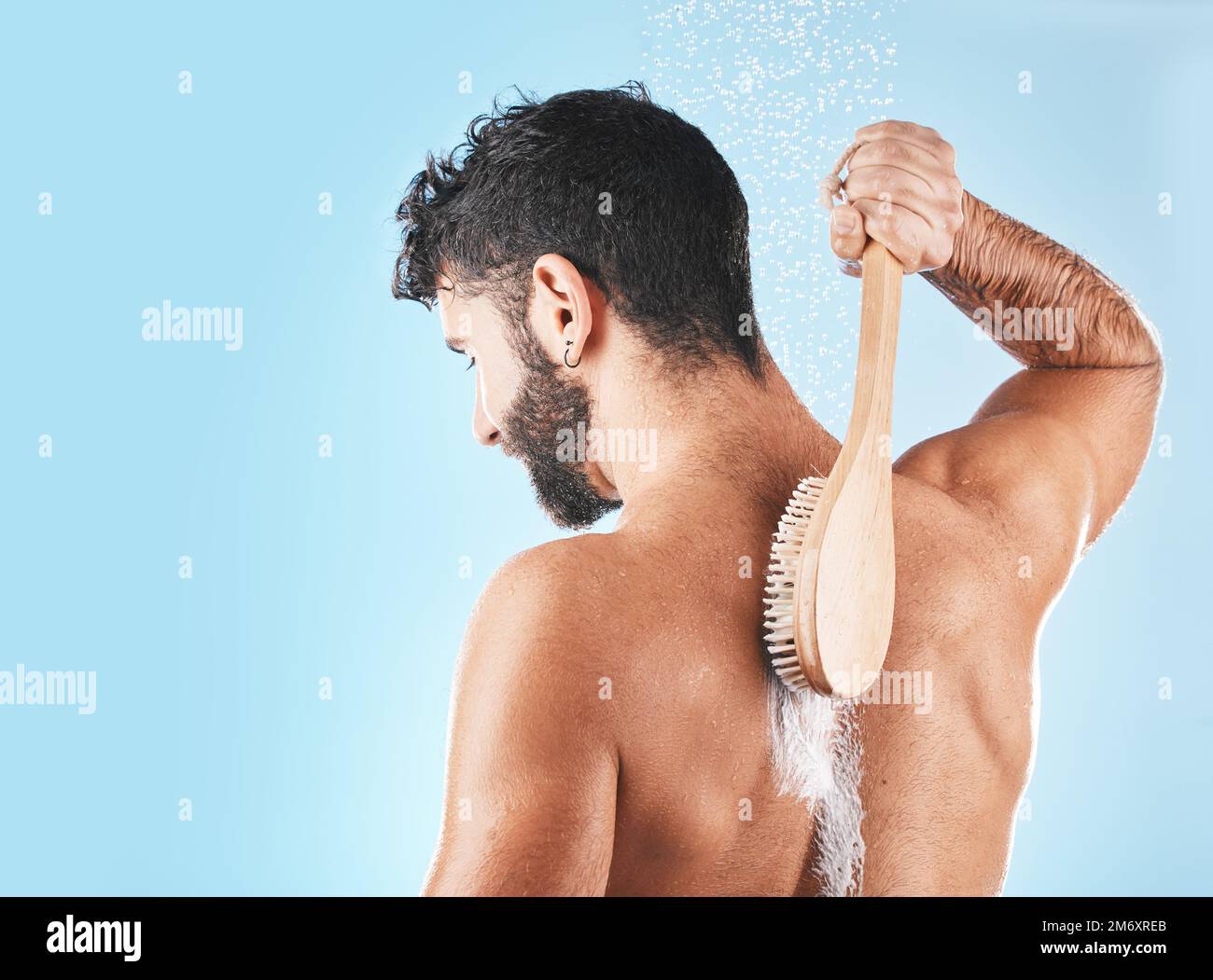 Shower, man and soap for body cleaning with brush in blue background studio, grooming hygiene ...