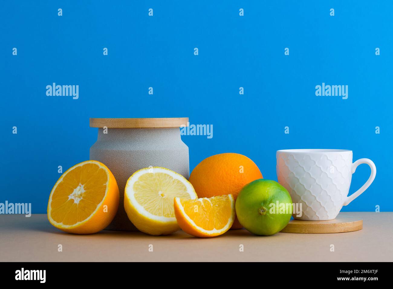 A front view of citrus decorated with wooden podium and tea in blue ...