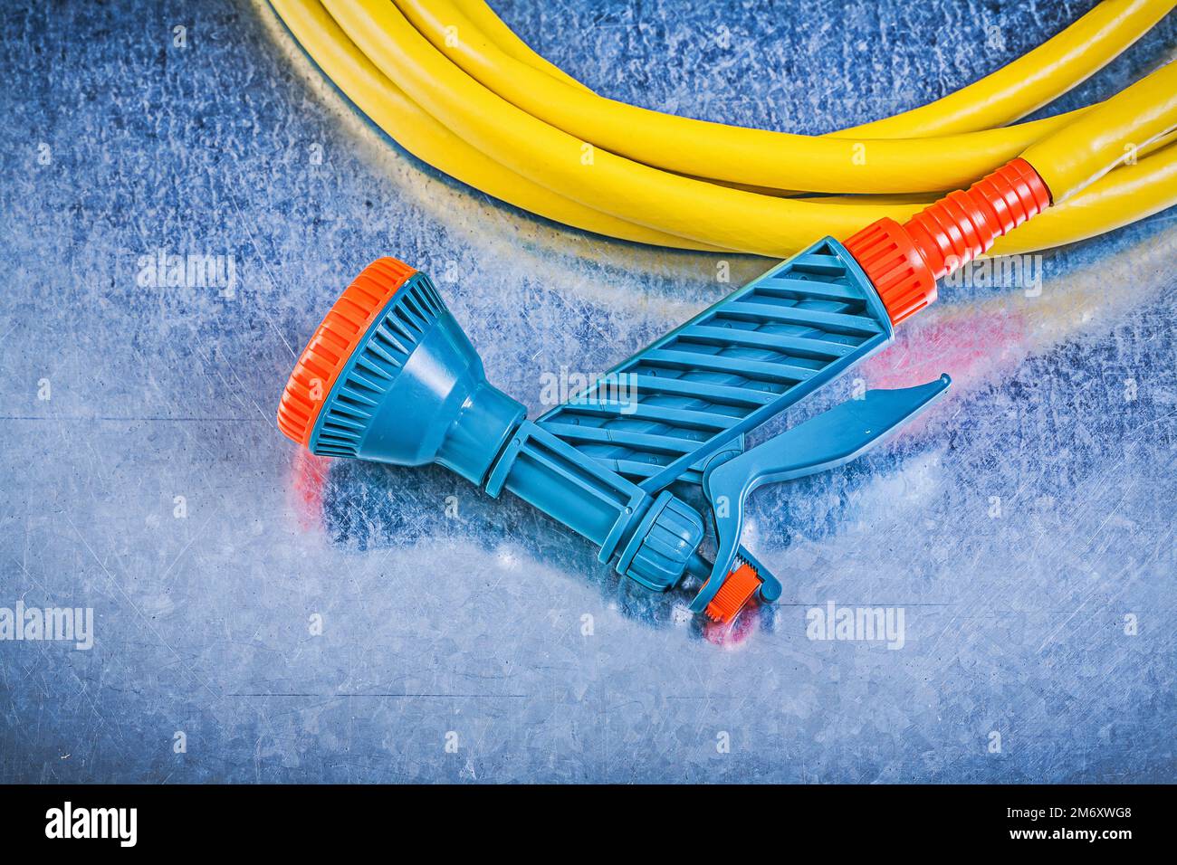 Hand spraying garden hose with spray nozzle on metallic background ...