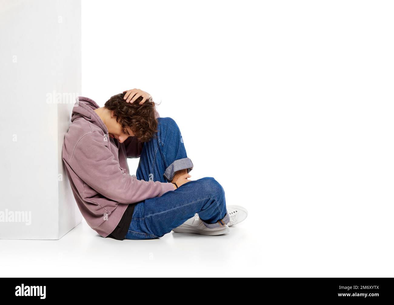 Portrait of young boy sitting on floor in depression and sadness over ...