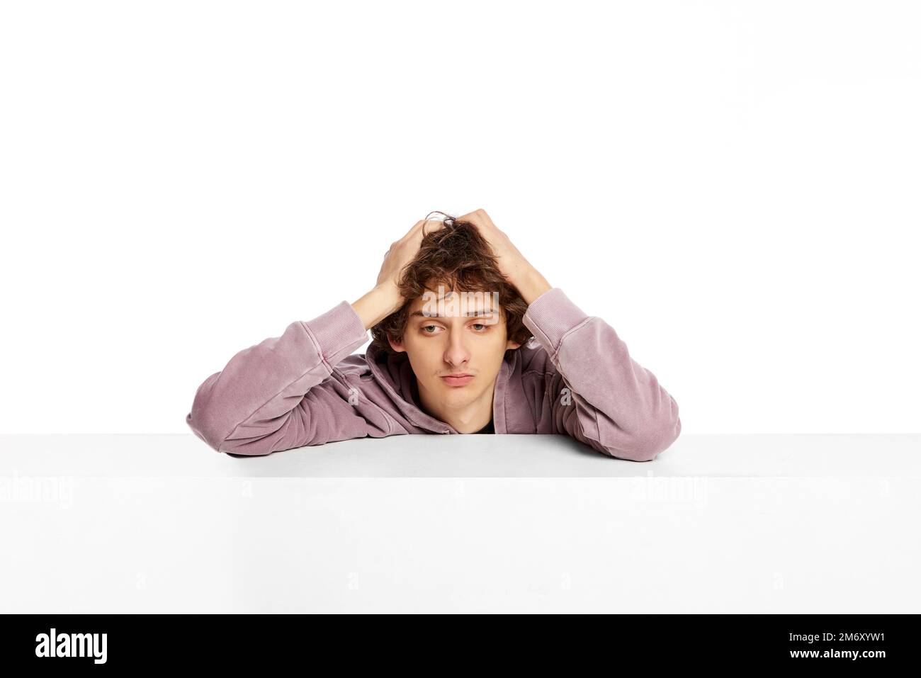 Portrait of young sad boy holding head with hands over white background ...