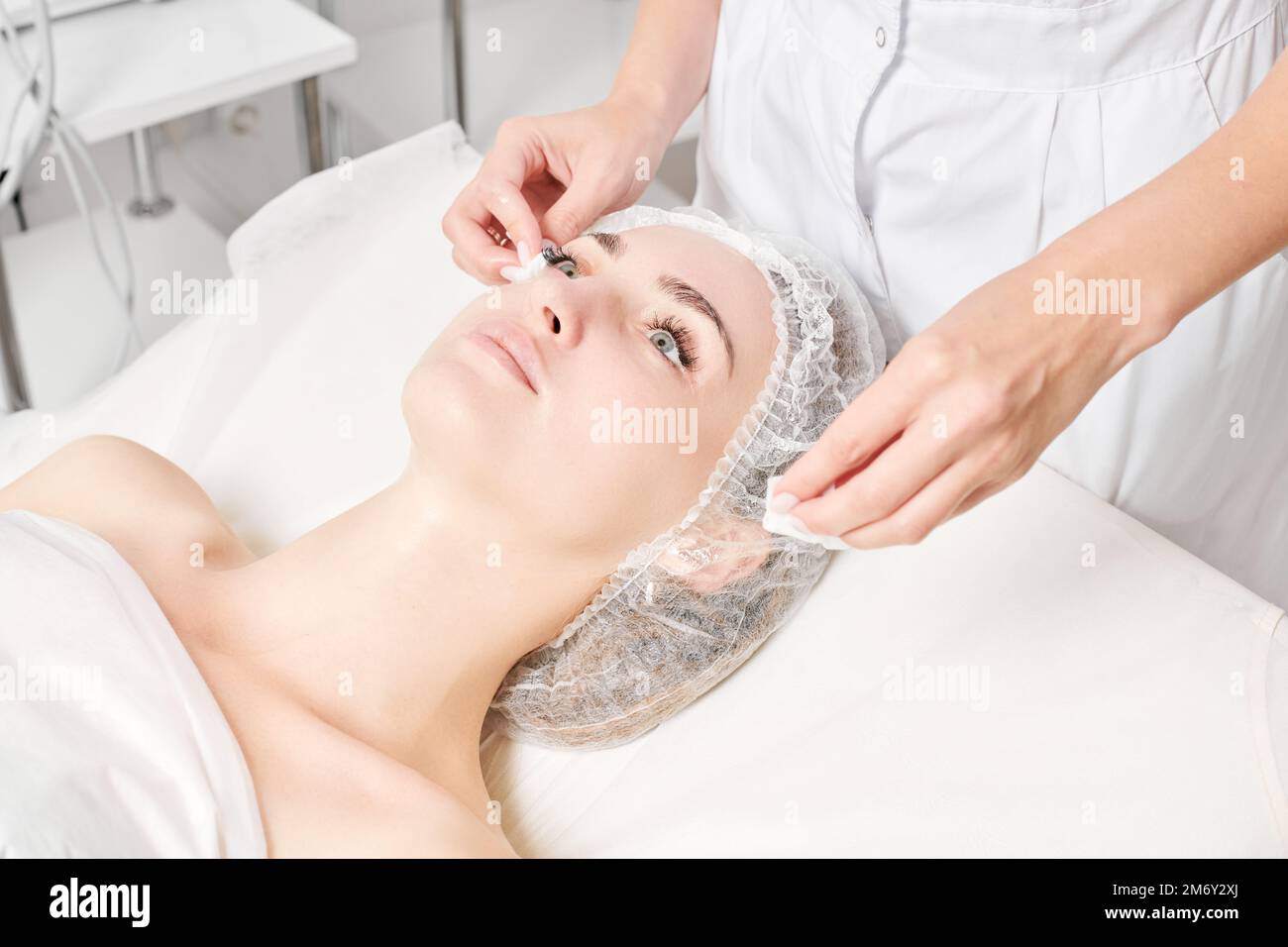 Beautician removing facial cream mask from woman face skin with ...