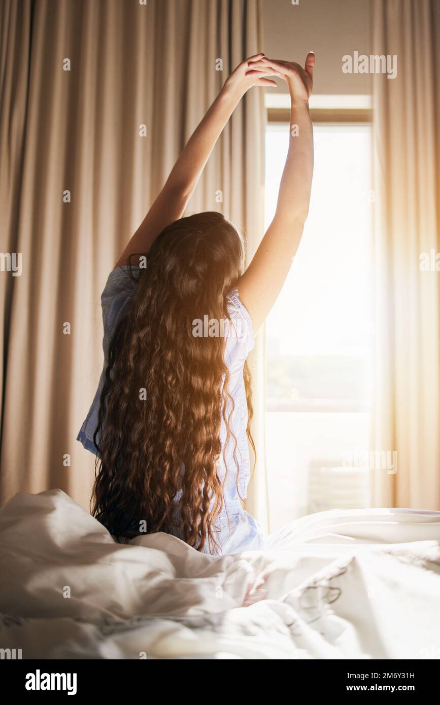 Morning, wake up and a woman stretching in the bedroom of her home ...