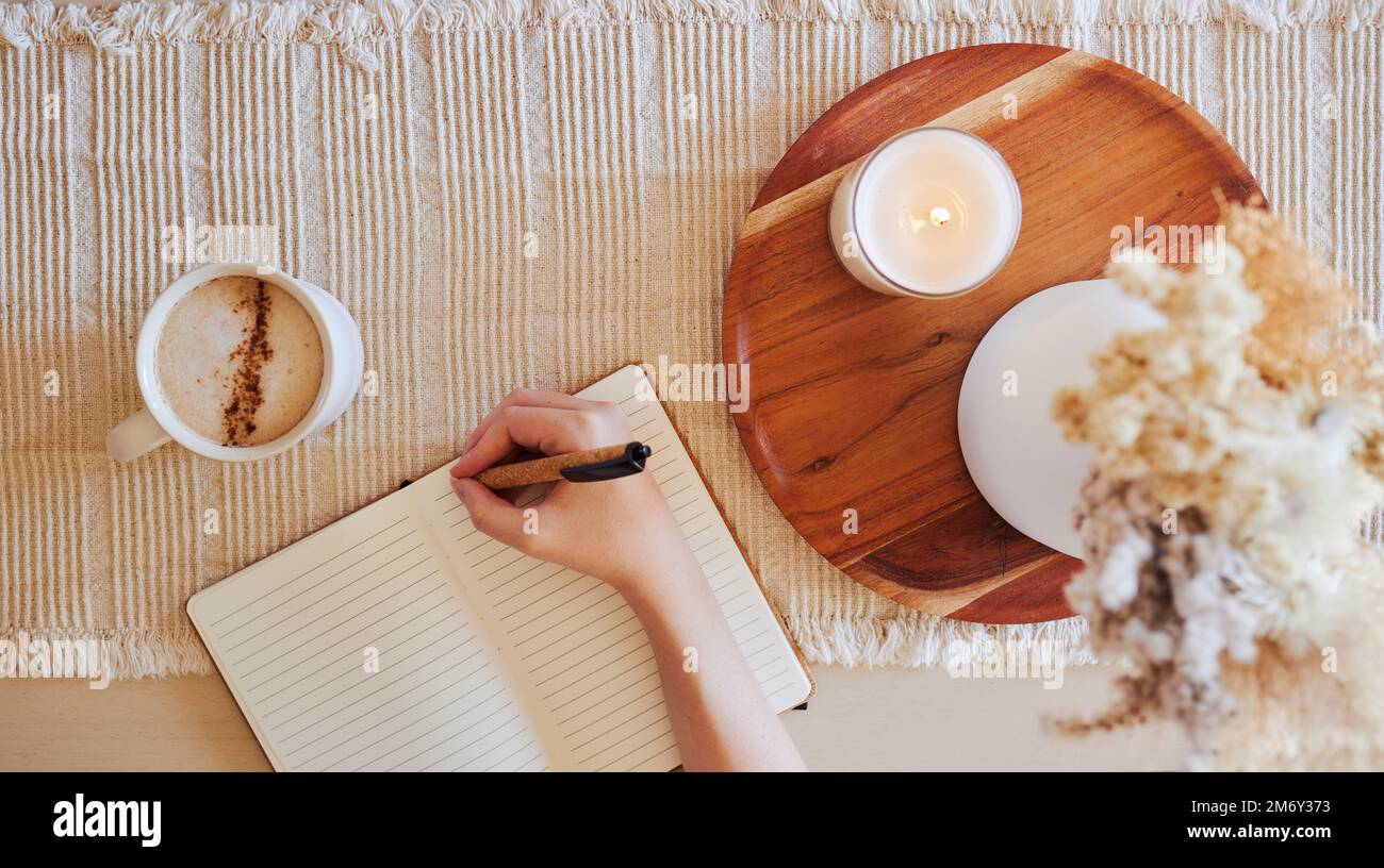 Coffee, hand and writing in journal top view with candle for calm ...