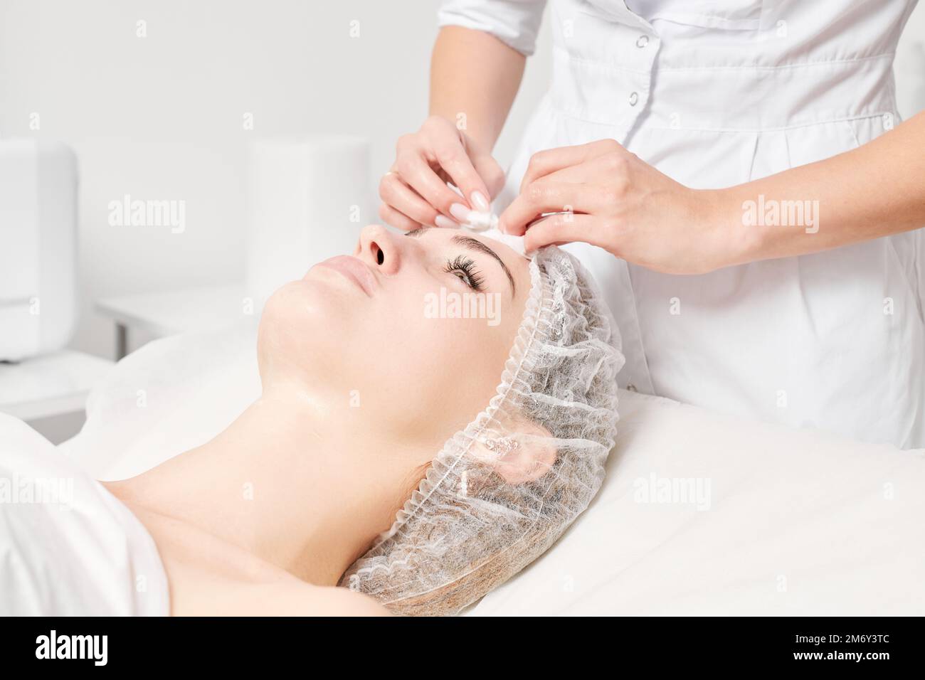 Beautician removing facial cream mask from woman face skin with ...