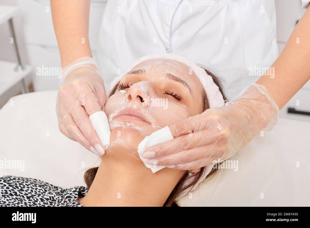 Beautician removing facial cream mask from woman face skin with ...
