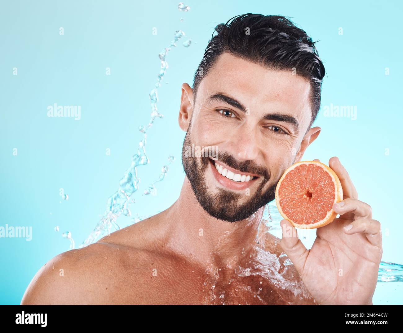 Skincare, water splash and portrait of man with grapefruit on blue background for vitamin c ...