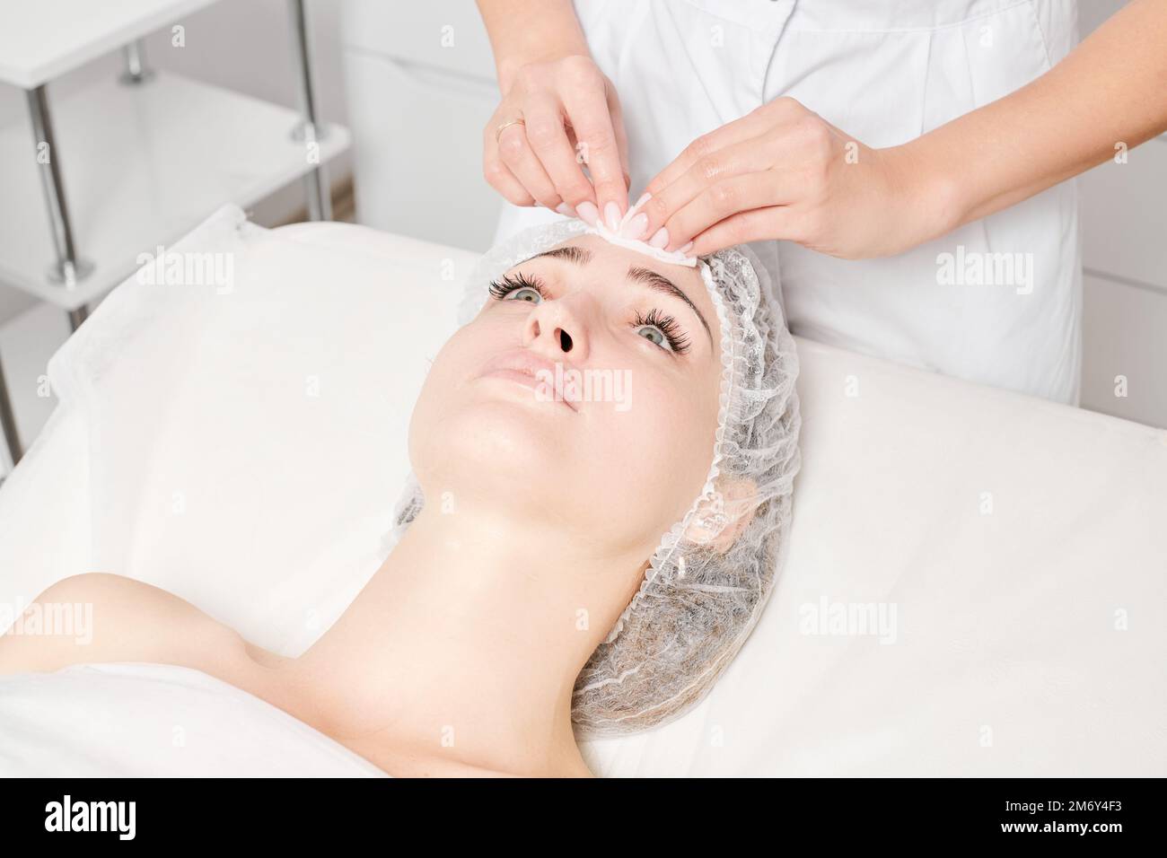 Beautician removing facial cream mask from woman face skin with ...