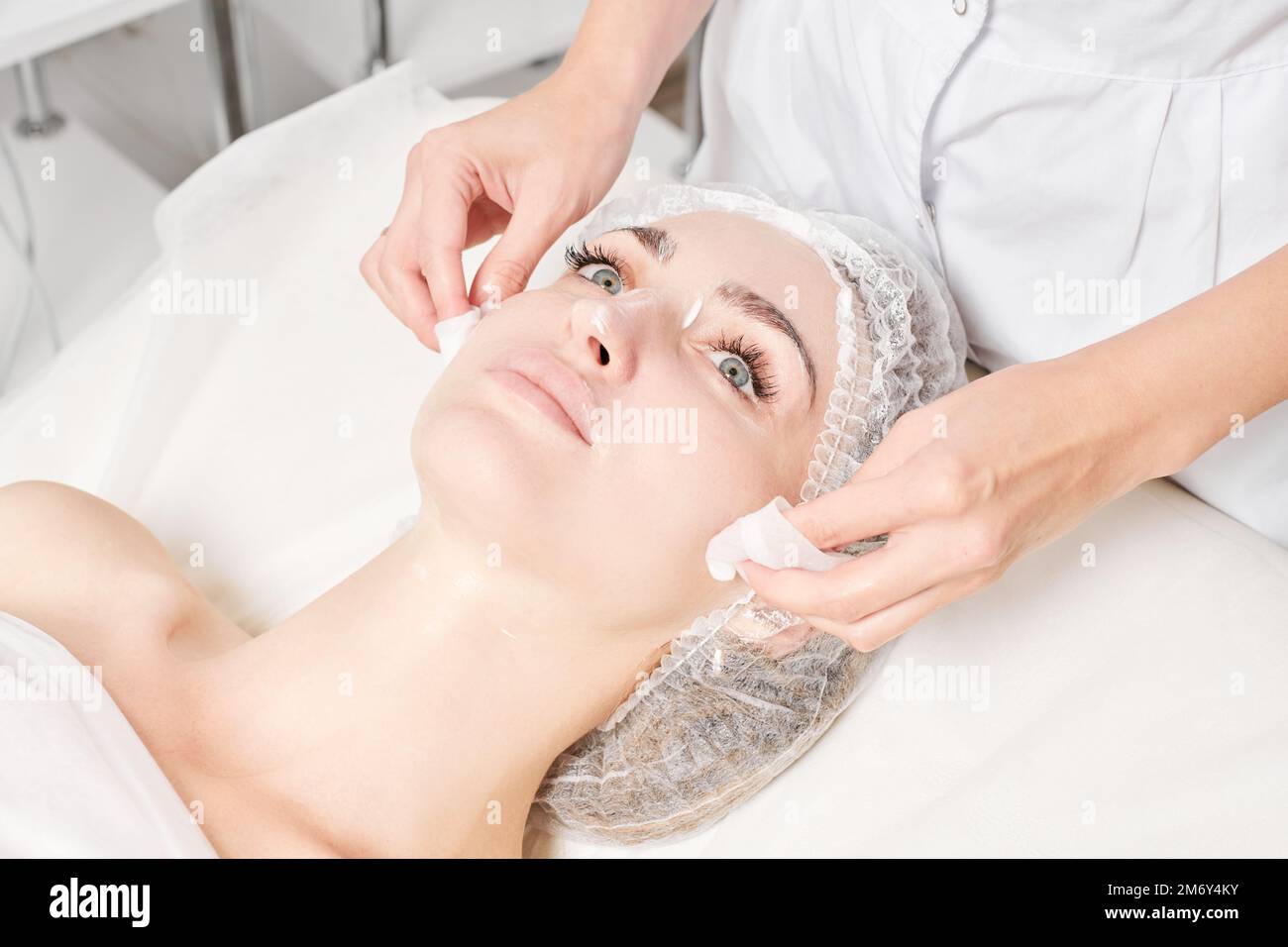 Beautician removing facial cream mask from woman face skin with ...