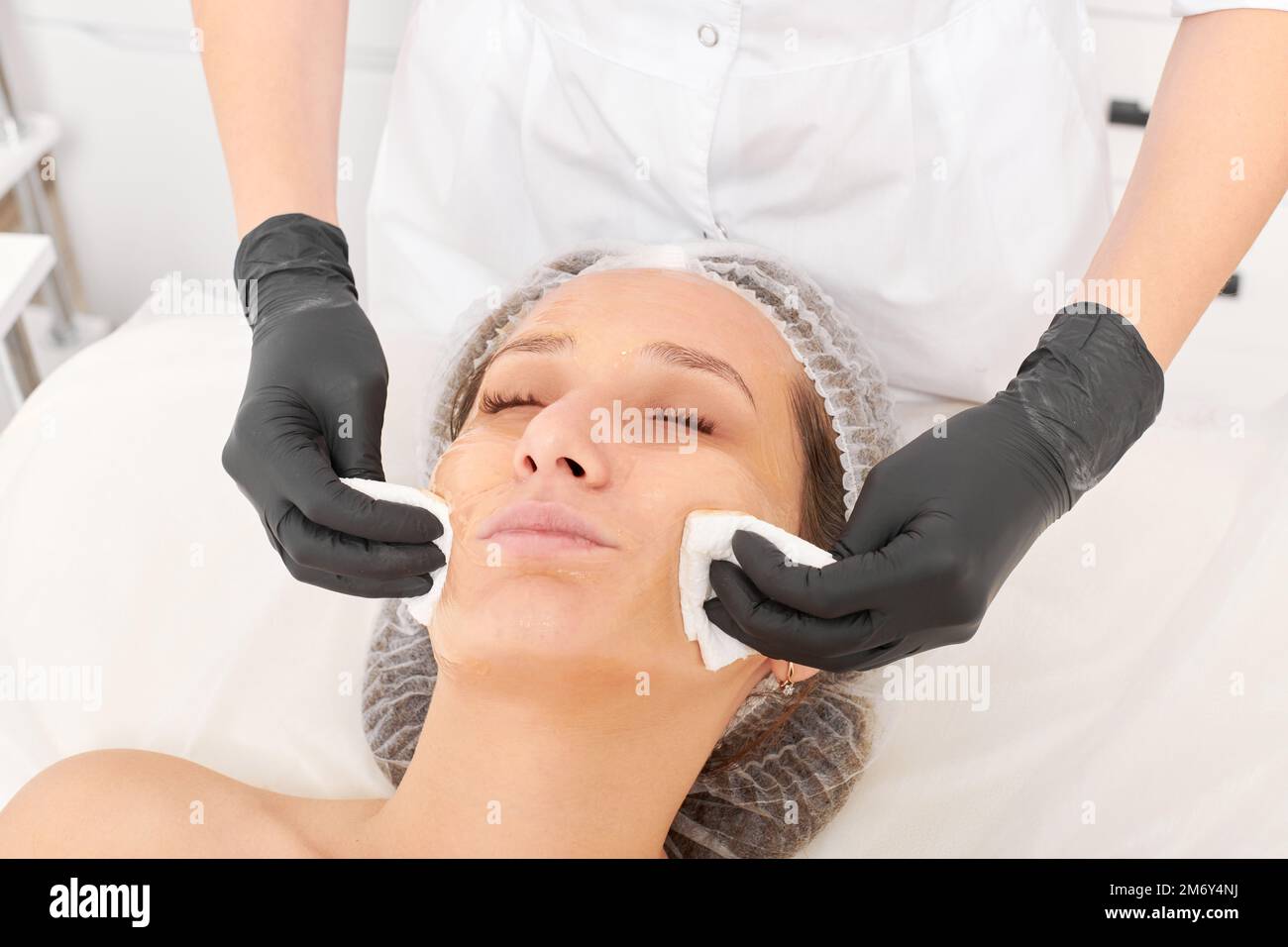 Beautician removing facial cream mask from woman face skin with ...