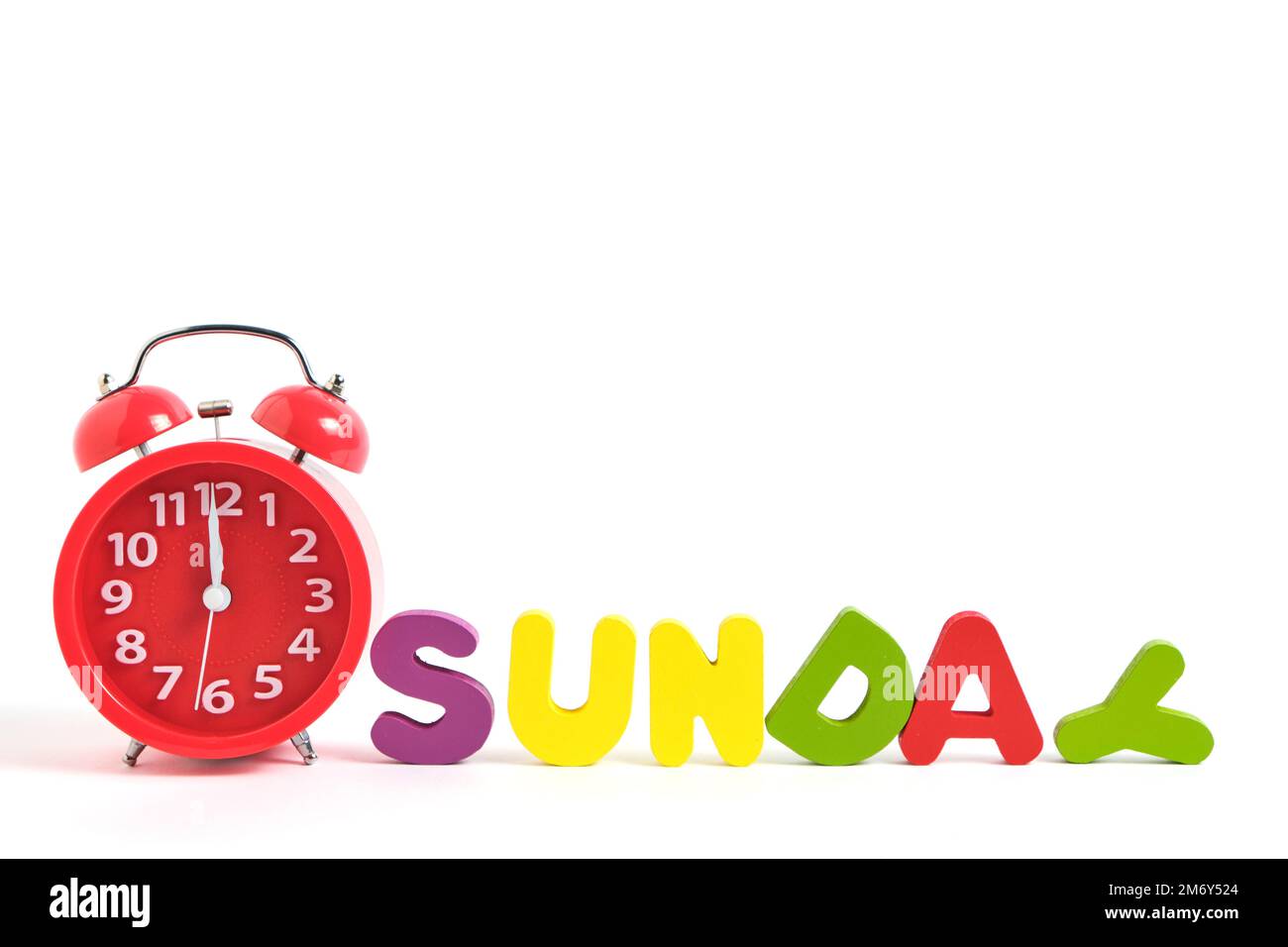 Twelve clock on red alarm clock and word Sunday made up letters white ...