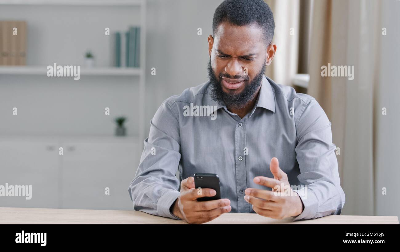 Stressed disappointed African American ethnic bearded man with mobile ...