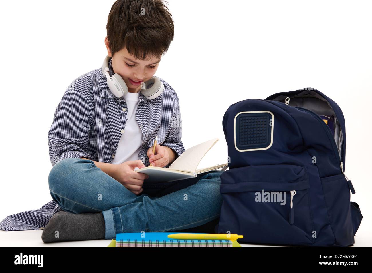 Smart pupil, teenage boy with wireless headphones, doing homework ...
