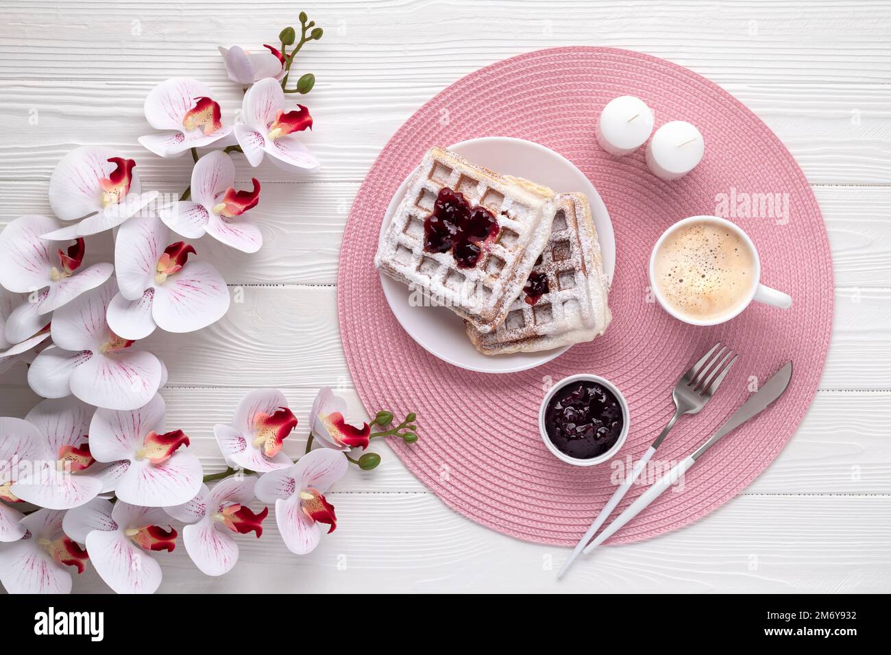 Belgian waffles with latte and blossom on white wooden table. Top view ...