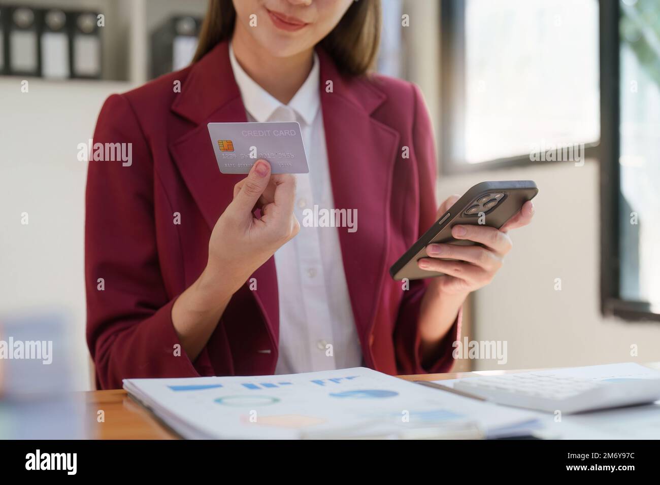 Asian woman using smartphone and credit card for online shopping. E ...