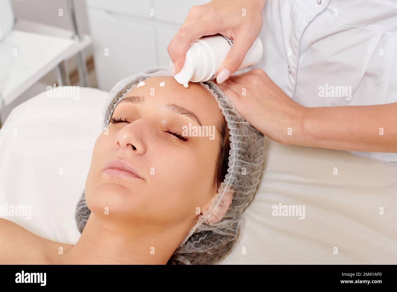 Beautician applying moisturizing cream on woman face for rejuvenation ...