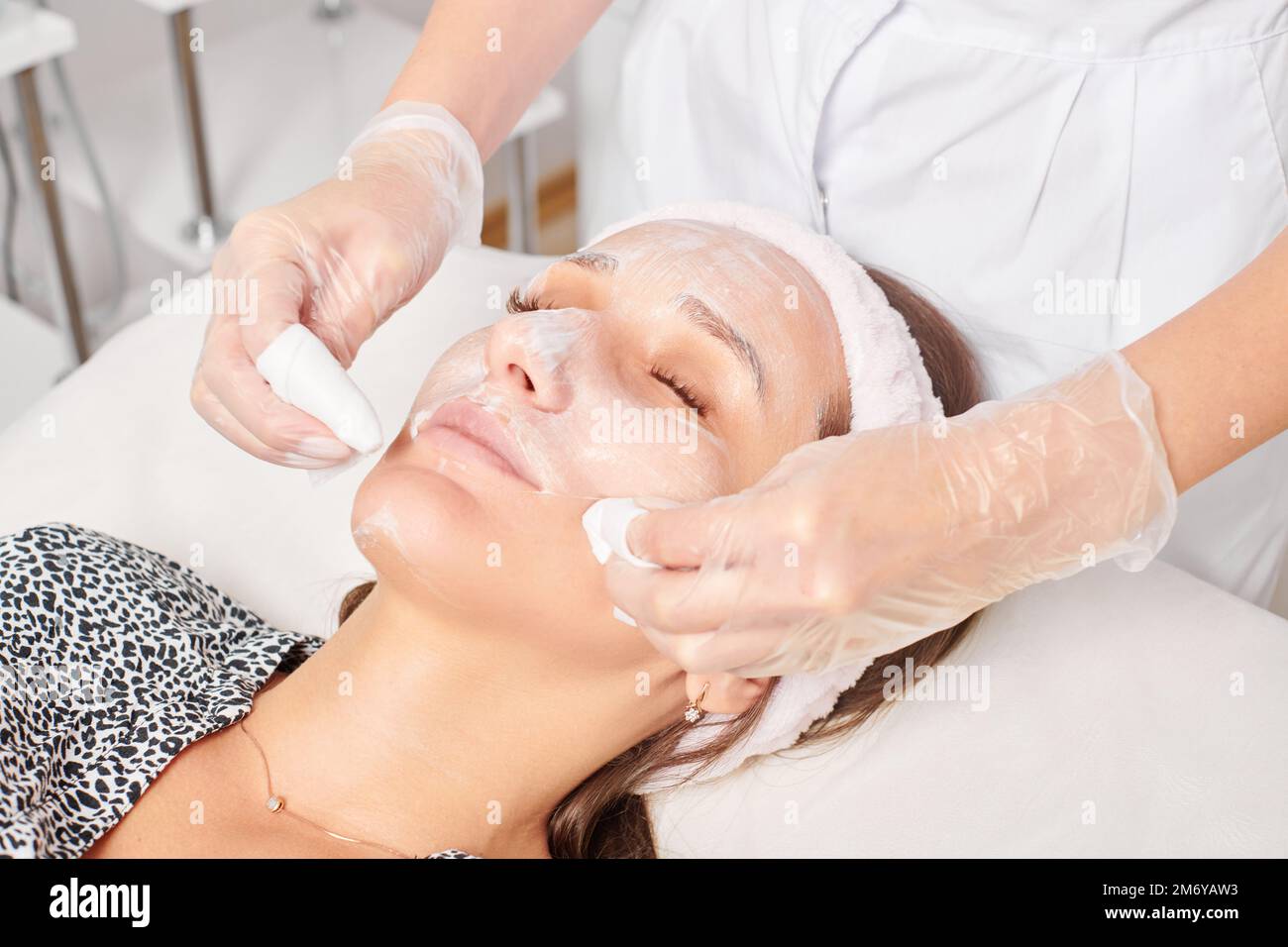 Beautician removing facial cream mask from woman face skin with ...