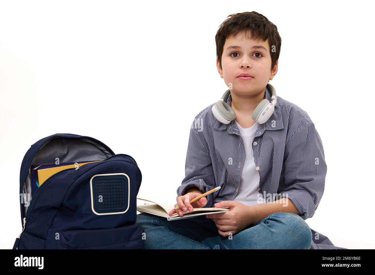 Adorable multi-ethnic teenage boy with headset, doing homework, looking ...
