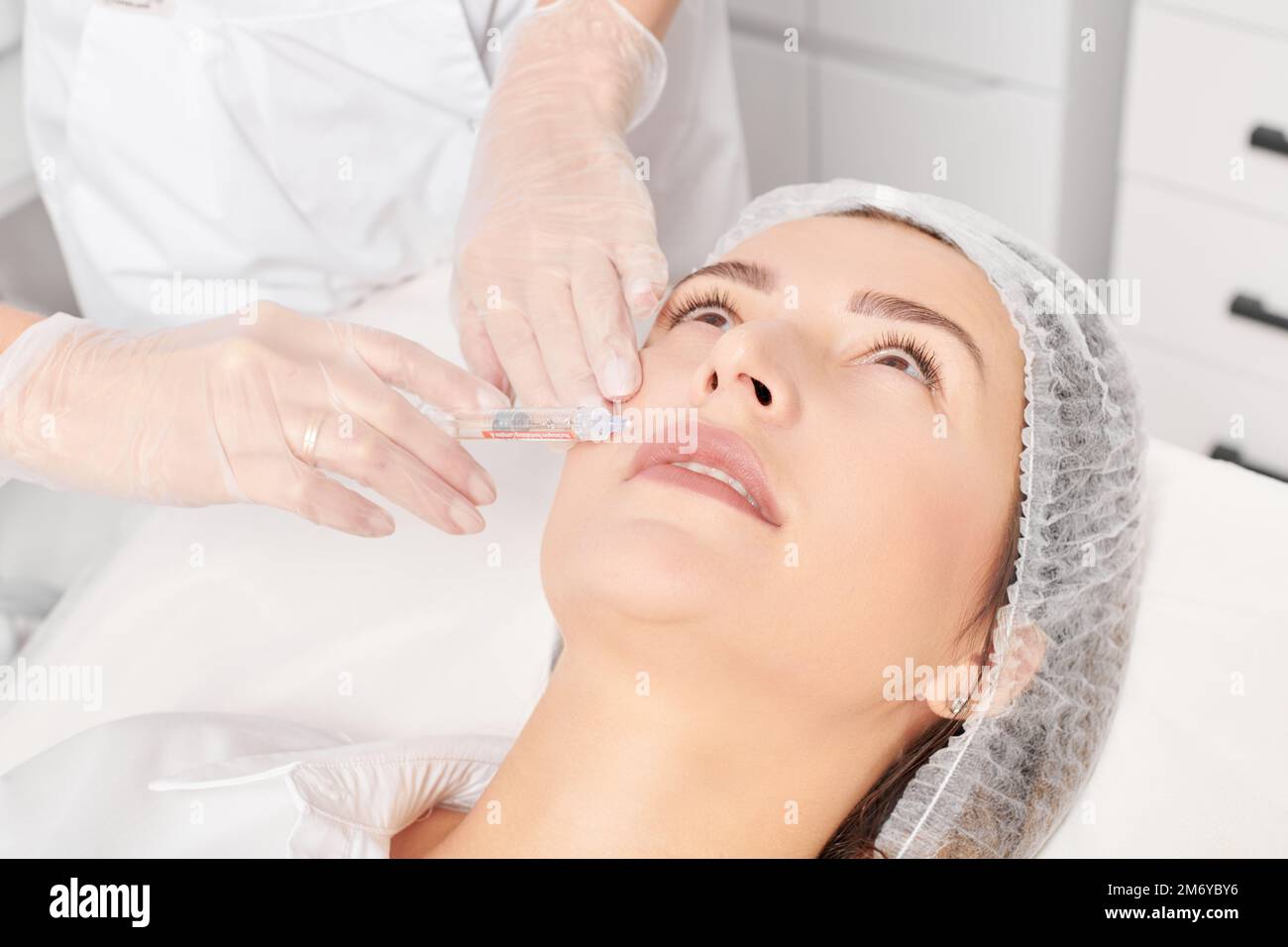 Cosmetologist makes rejuvenation injection in woman face skin, anti ...