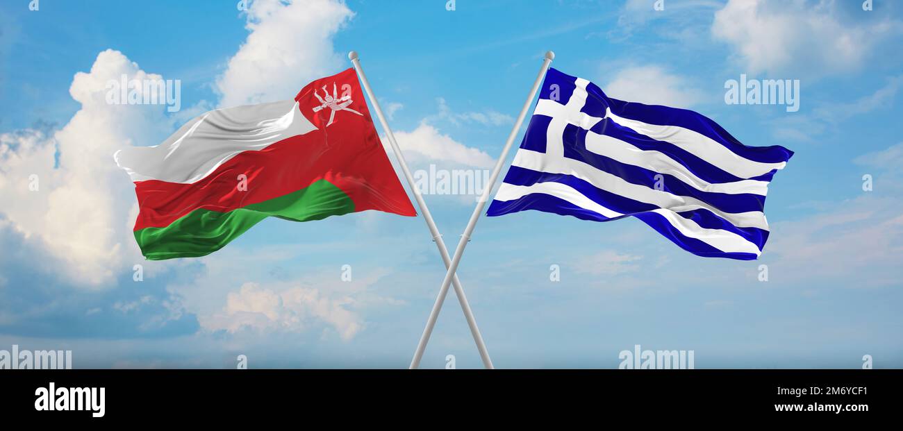 two crossed flags Greece and Oman waving in wind at cloudy sky. Concept ...
