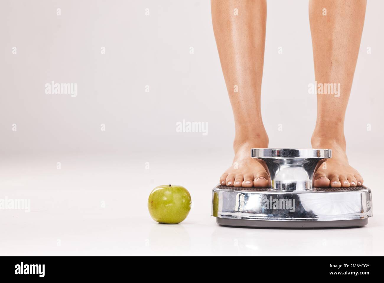 Feet, scale and apple in studio on a gray background with mockup for ...