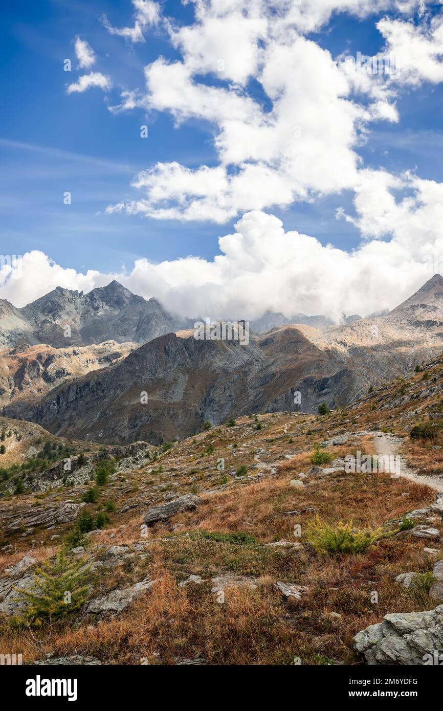 Alpine hiking path on mountain slope covered with withered autumn grass ...