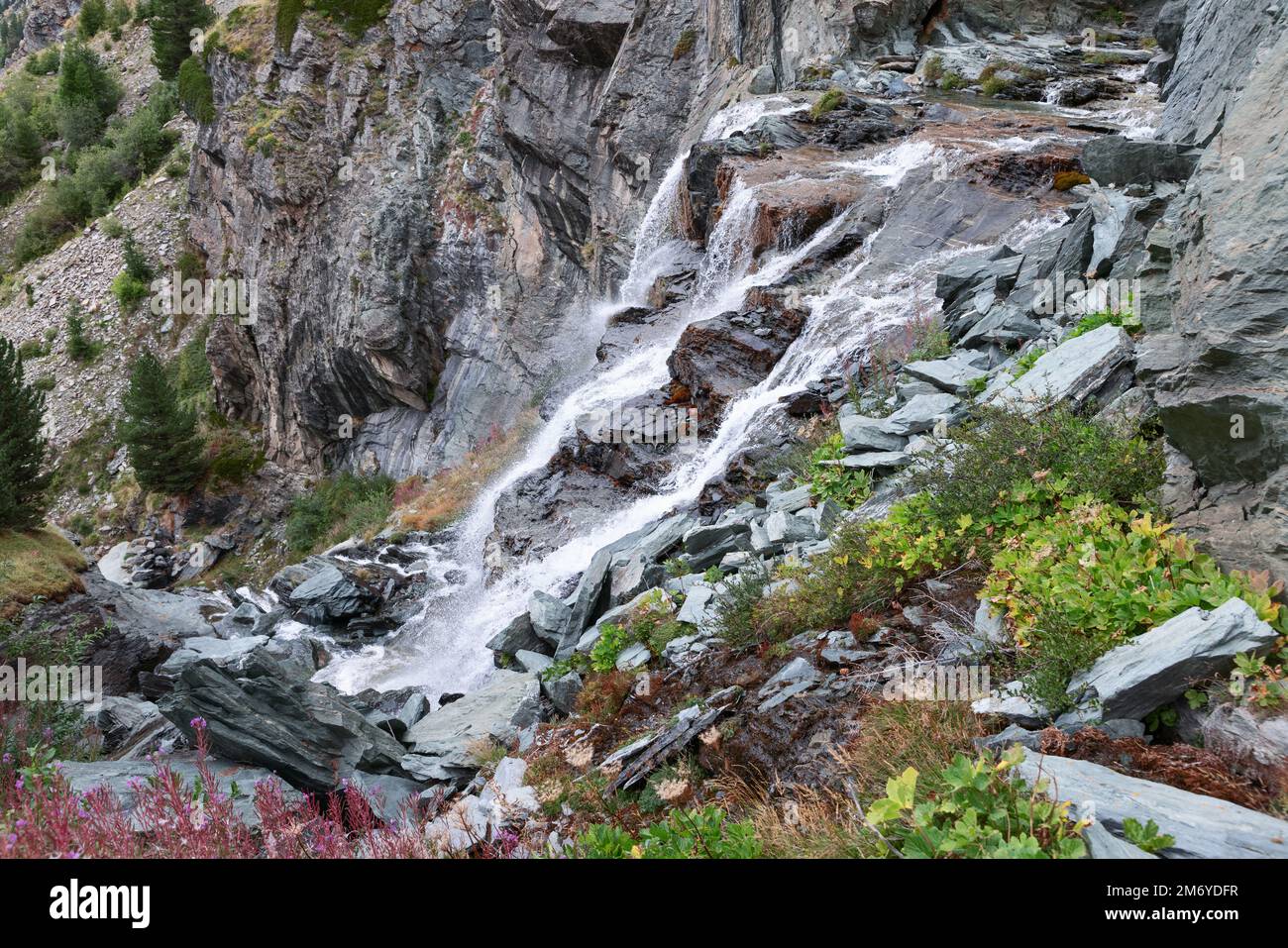 Foaming contrasting streams of alpine waterfall flowing over granite ...