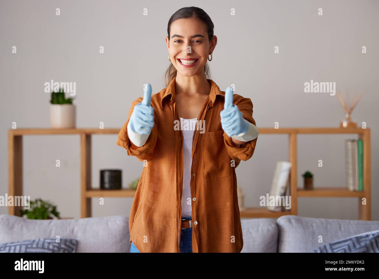 Happy woman, thumbs up and cleaning service with a smile in a house or ...