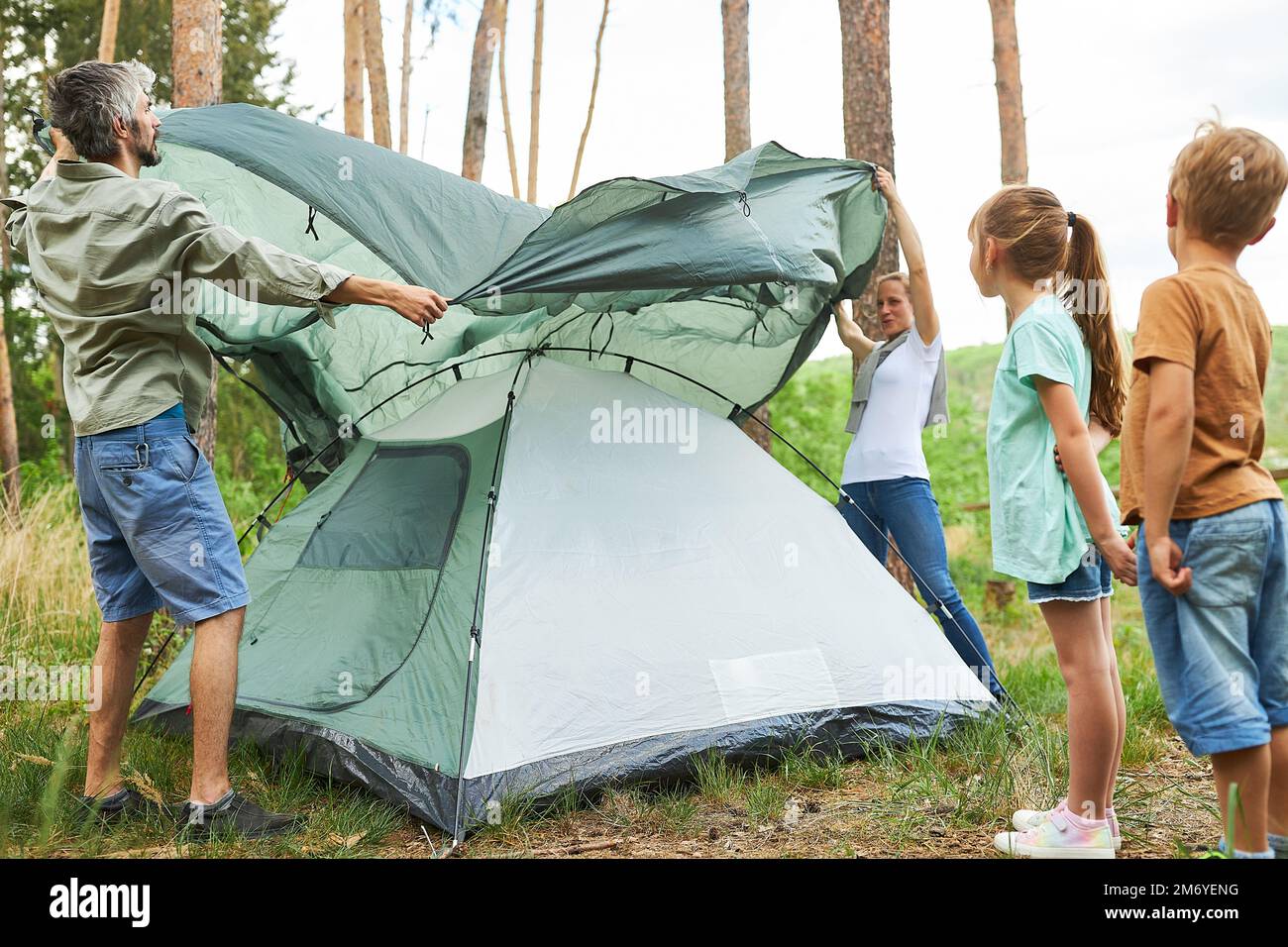 Children with mother and father setting up tent for camping in nature ...