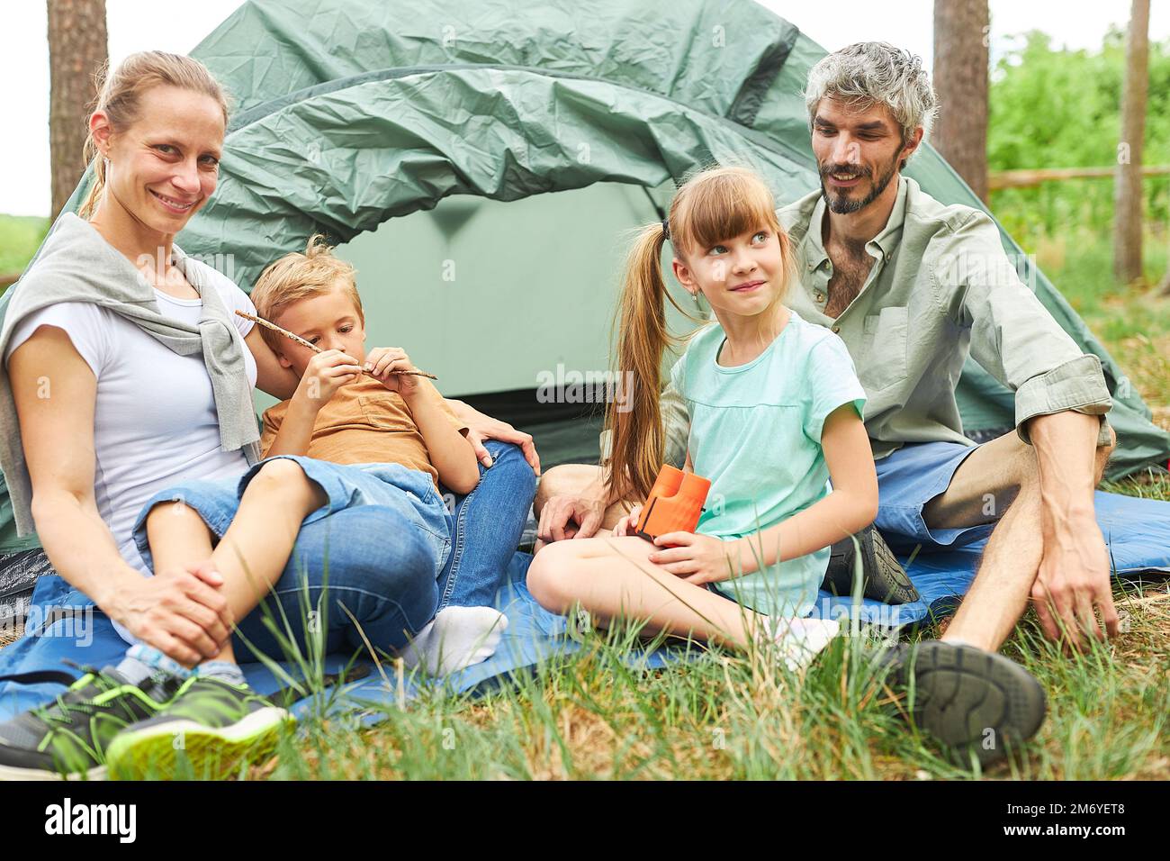Parents spending leisure time with children while sitting outside tent ...