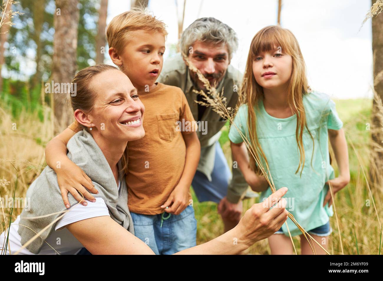 Happy family with children hiking in nature and making discovery in ...