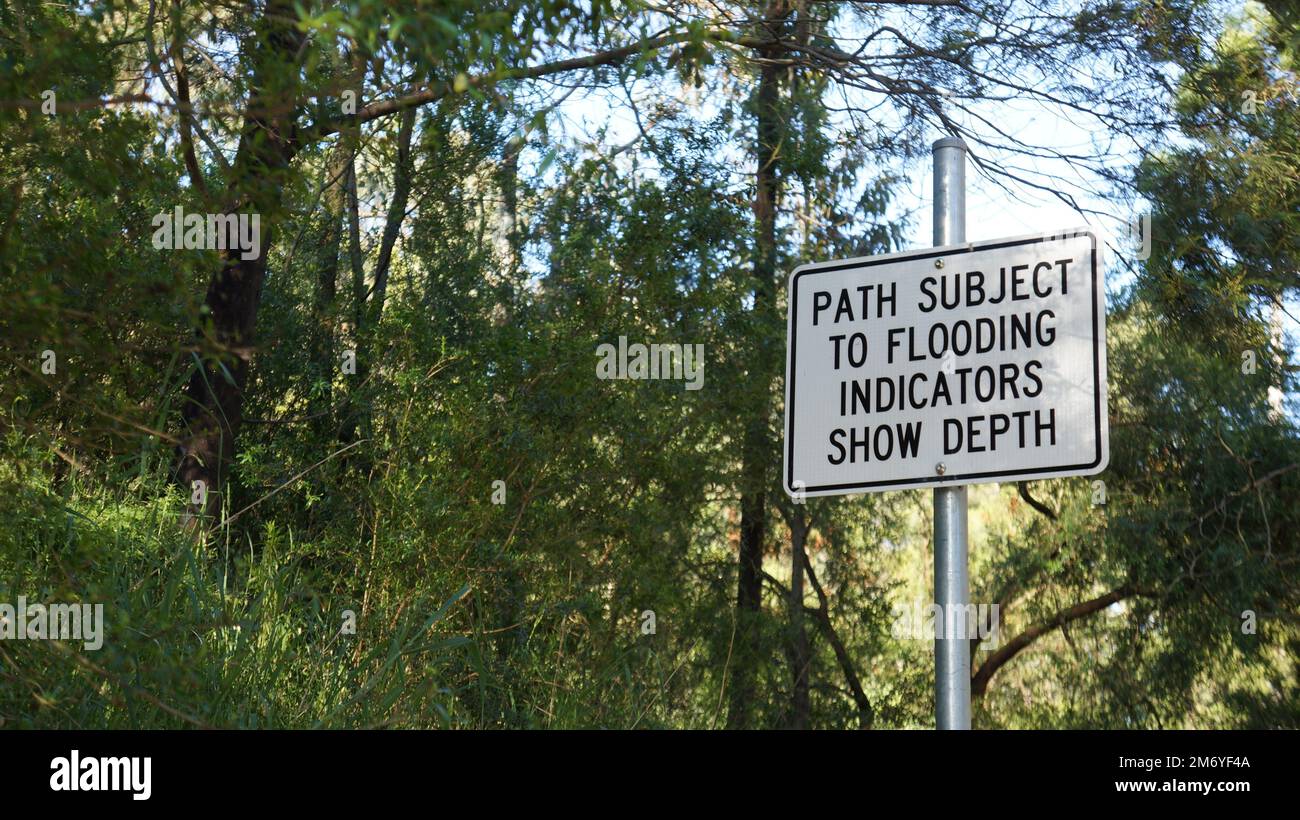 A flood warning sign in background of dense trees Stock Photo - Alamy